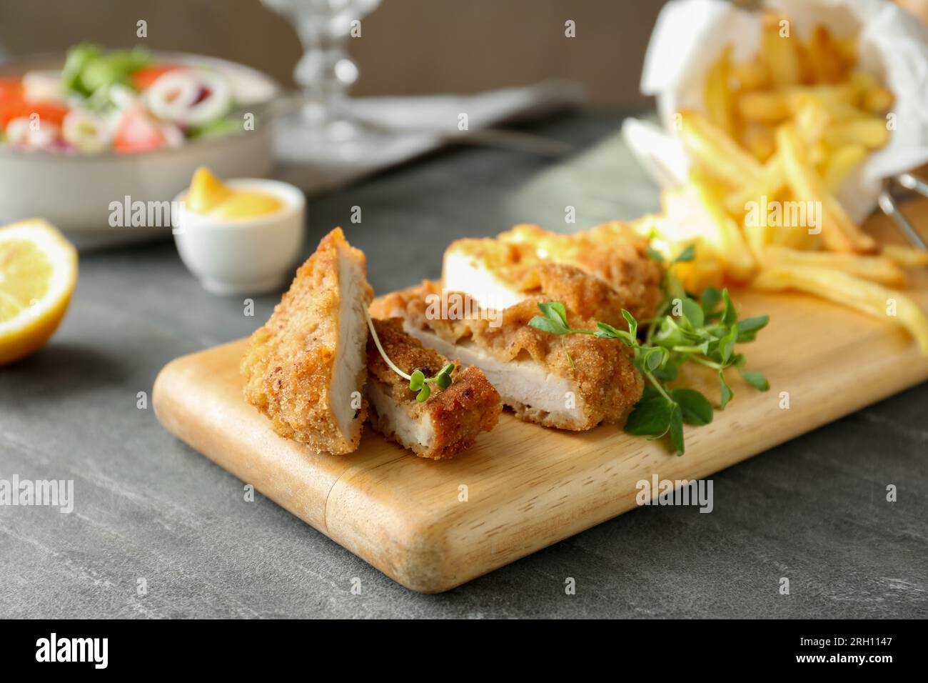 Delicious cut schnitzel served with microgreens on grey table Stock ...