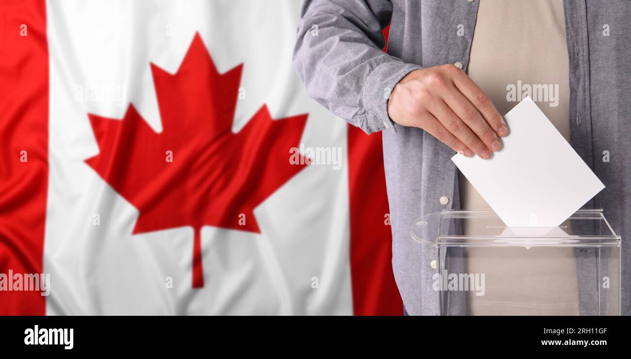 Man putting his vote into ballot box against national flag of Canada ...