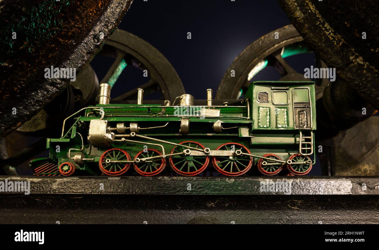 Green steam locomotive model with red wheels under a set of old steam ...