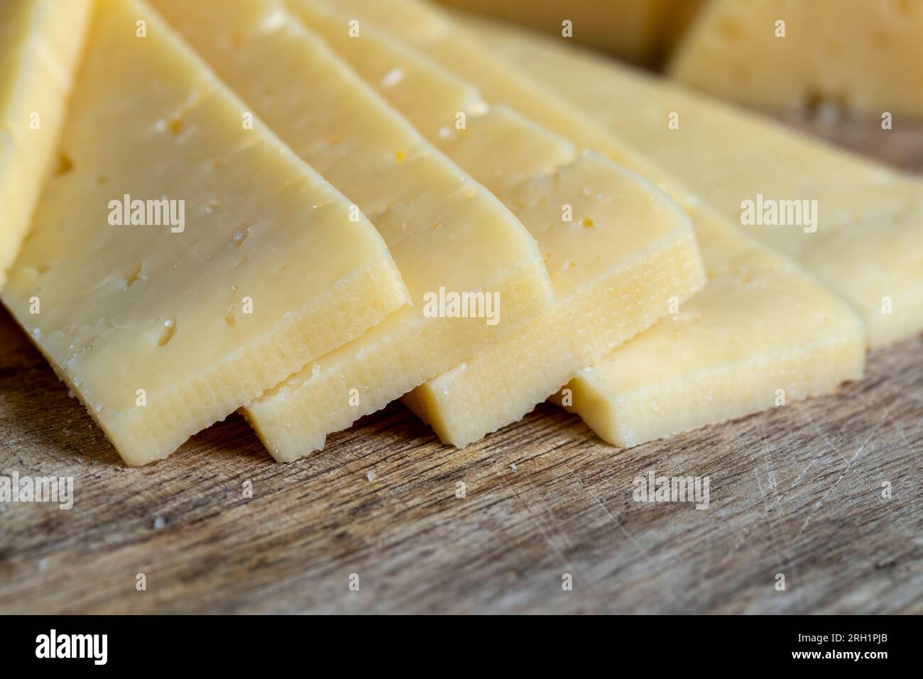 sliced natural cow's milk cheese, fresh yellow milk cheese on a board ...
