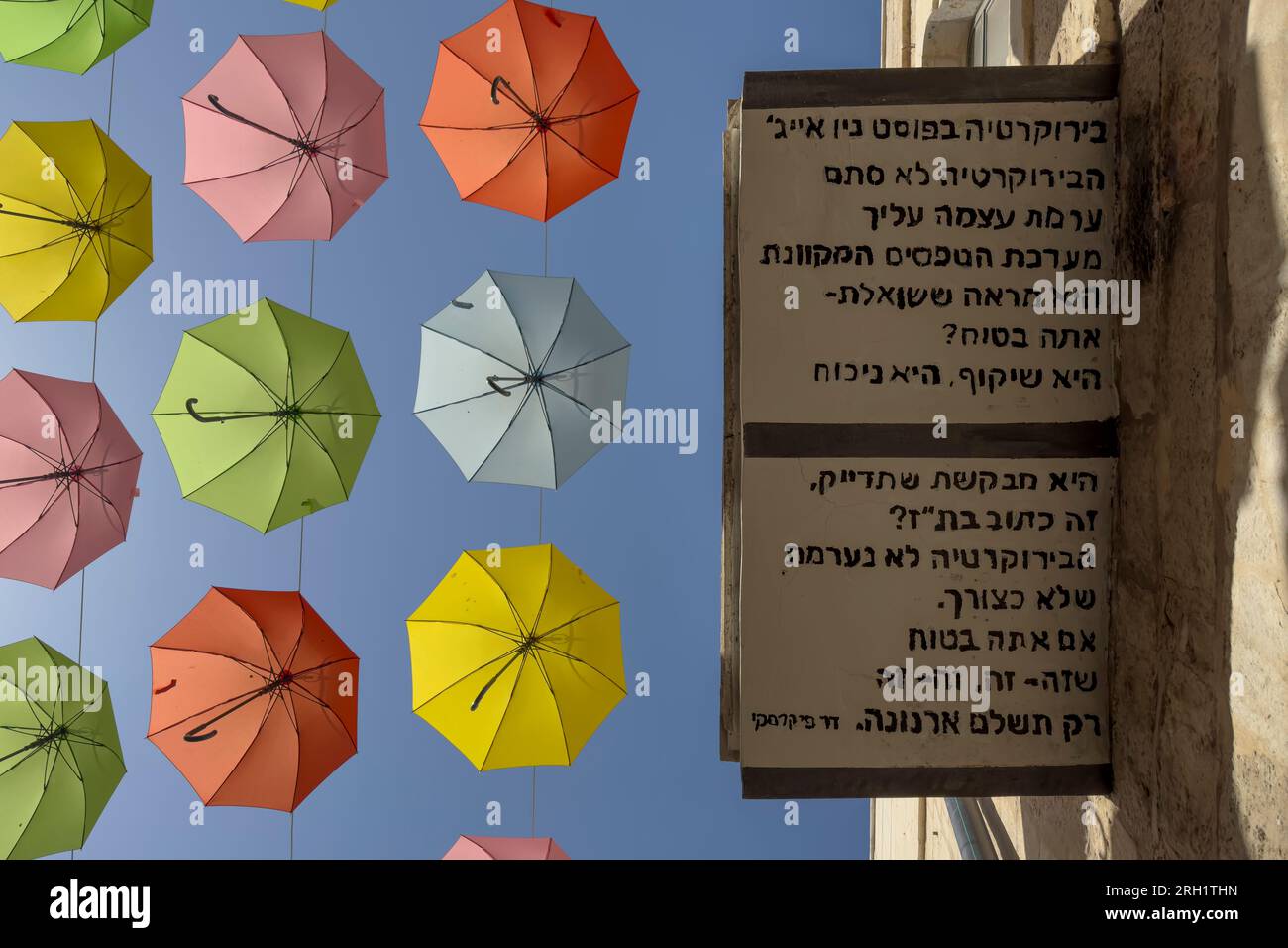 Quote of a poem in Hebrew written beneath a balcony with colorful ...