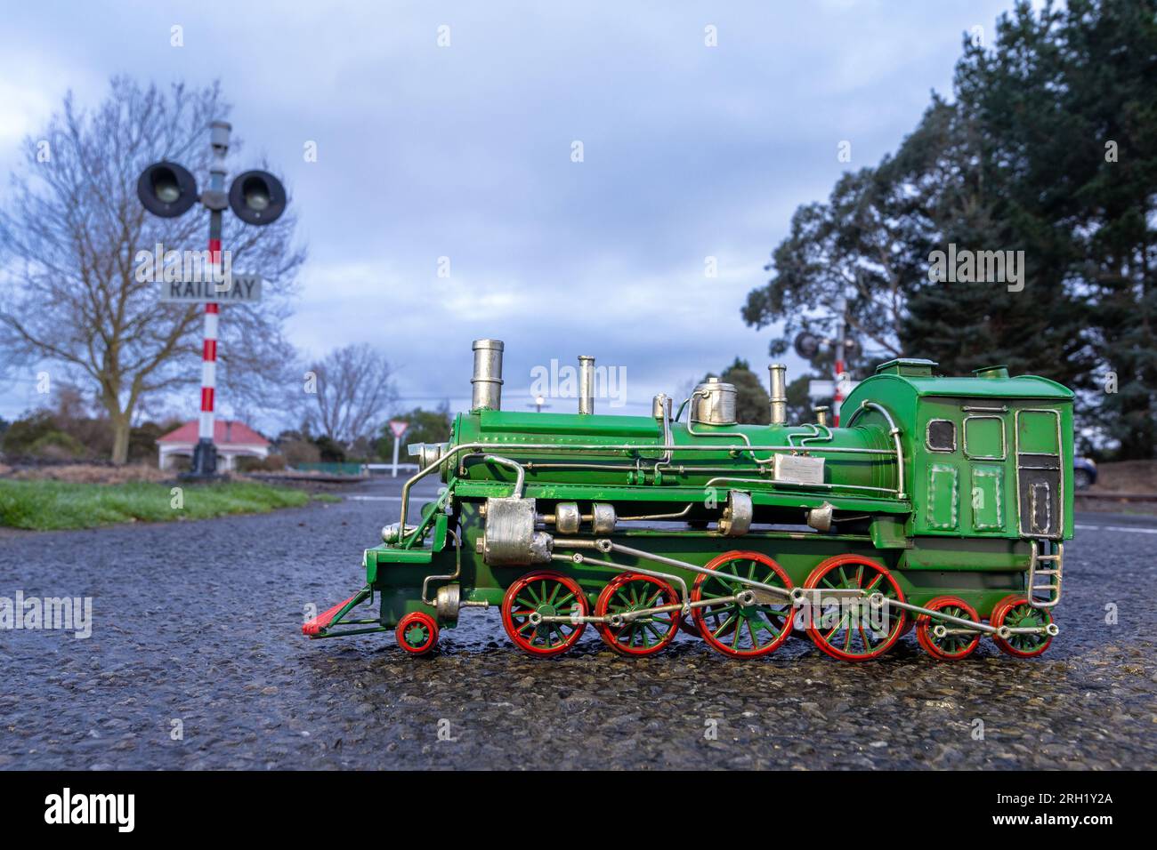 Green steam locomotive with red wheels at a railway track crossing ...