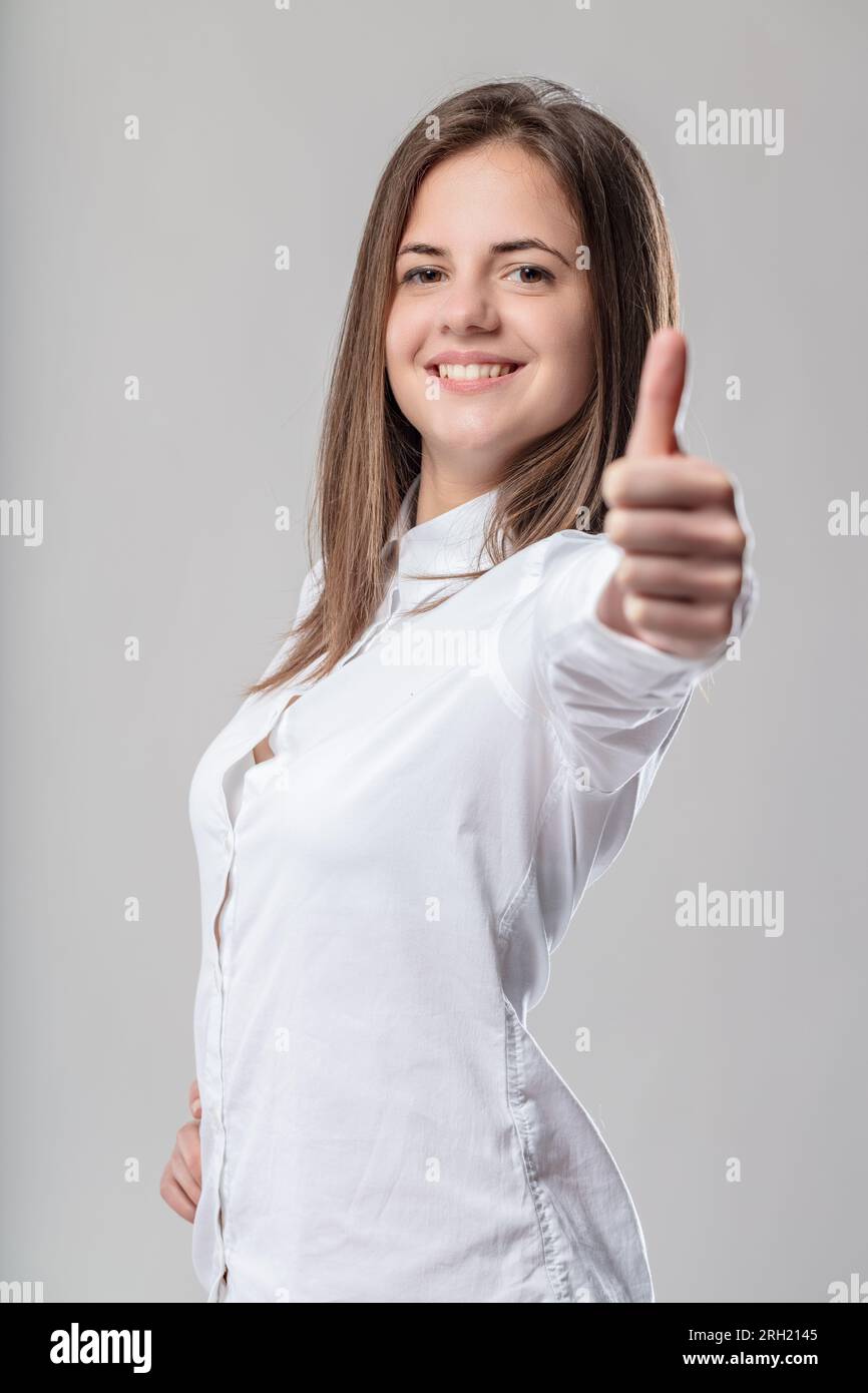 Fit woman, white shirt and shorts, smiles, thumbs up for agreement ...
