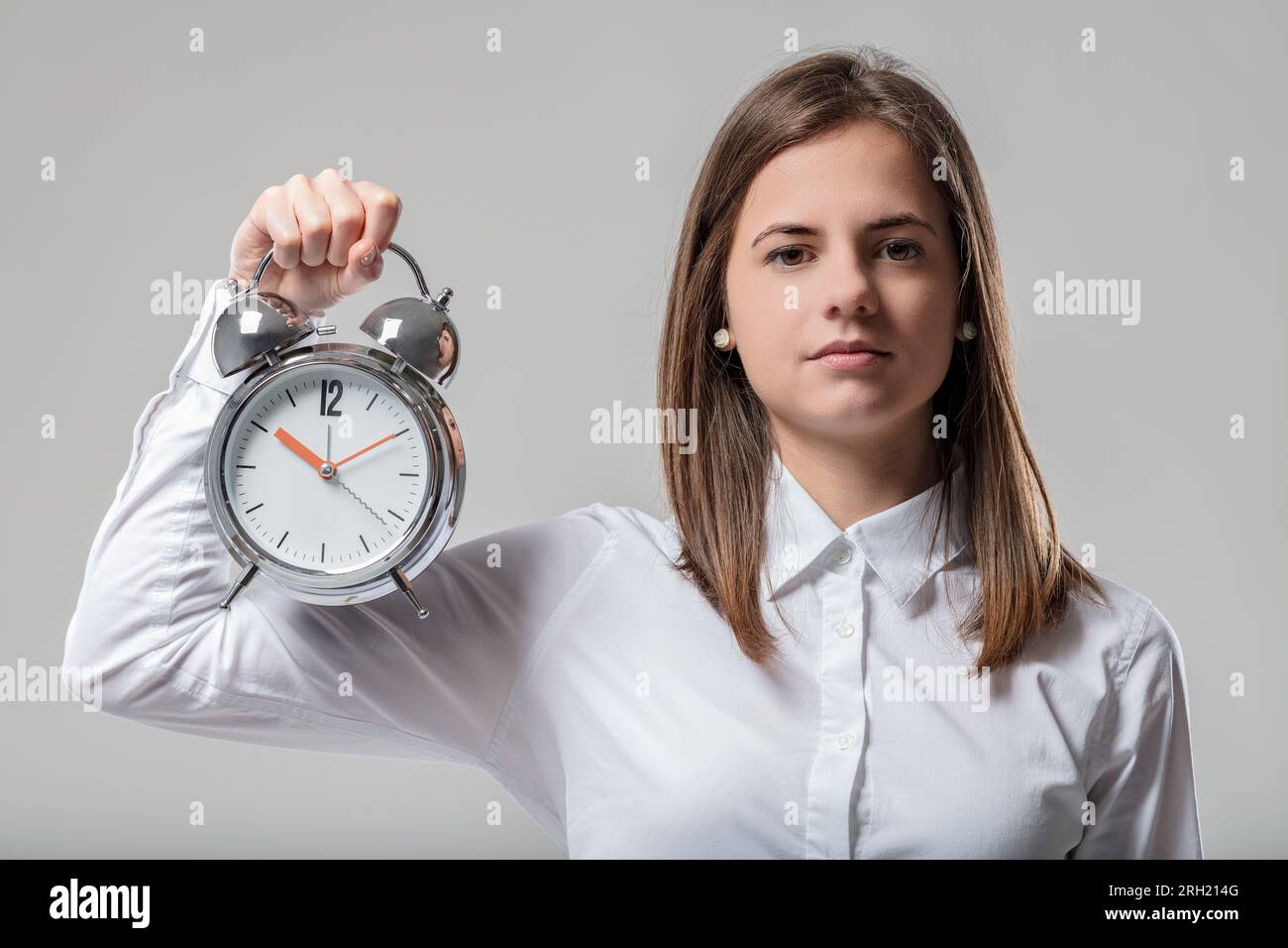 Woman with medium-length brown hair and white shirt holding big alarm ...
