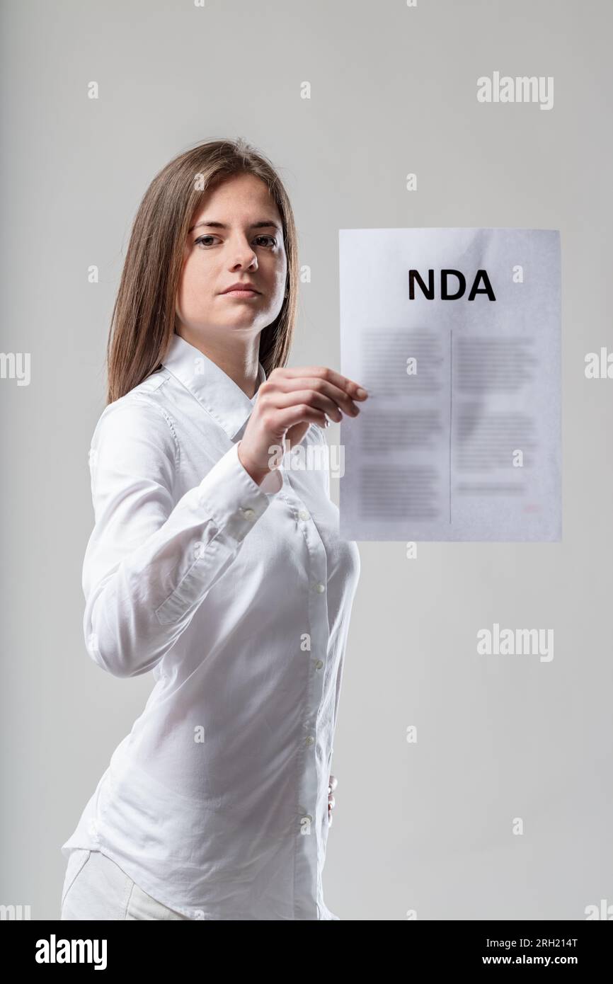 Focus on NDA, held by woman in white, warning about speech restriction ...