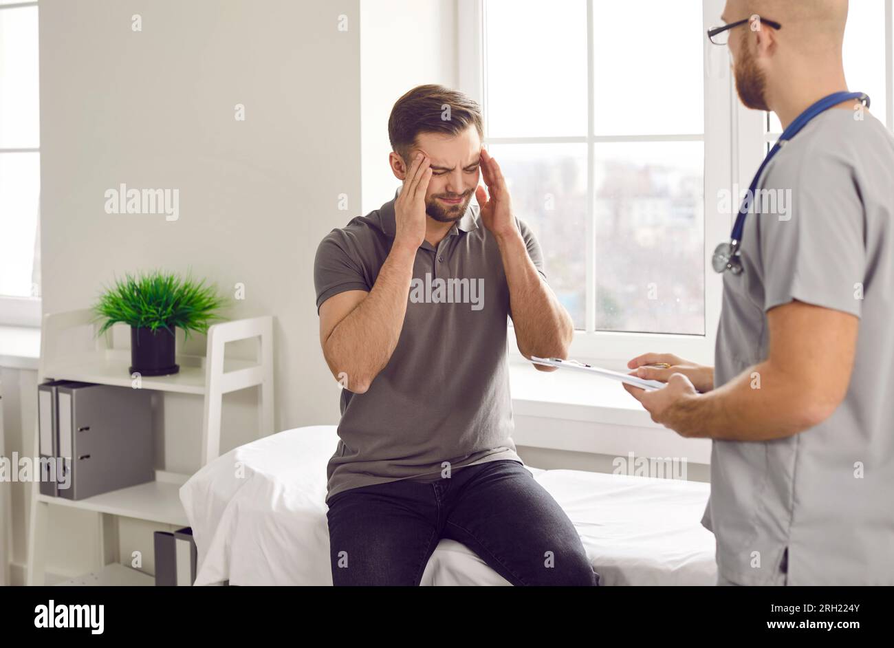 Young male patient is suffering from headache and asking doctor at ...