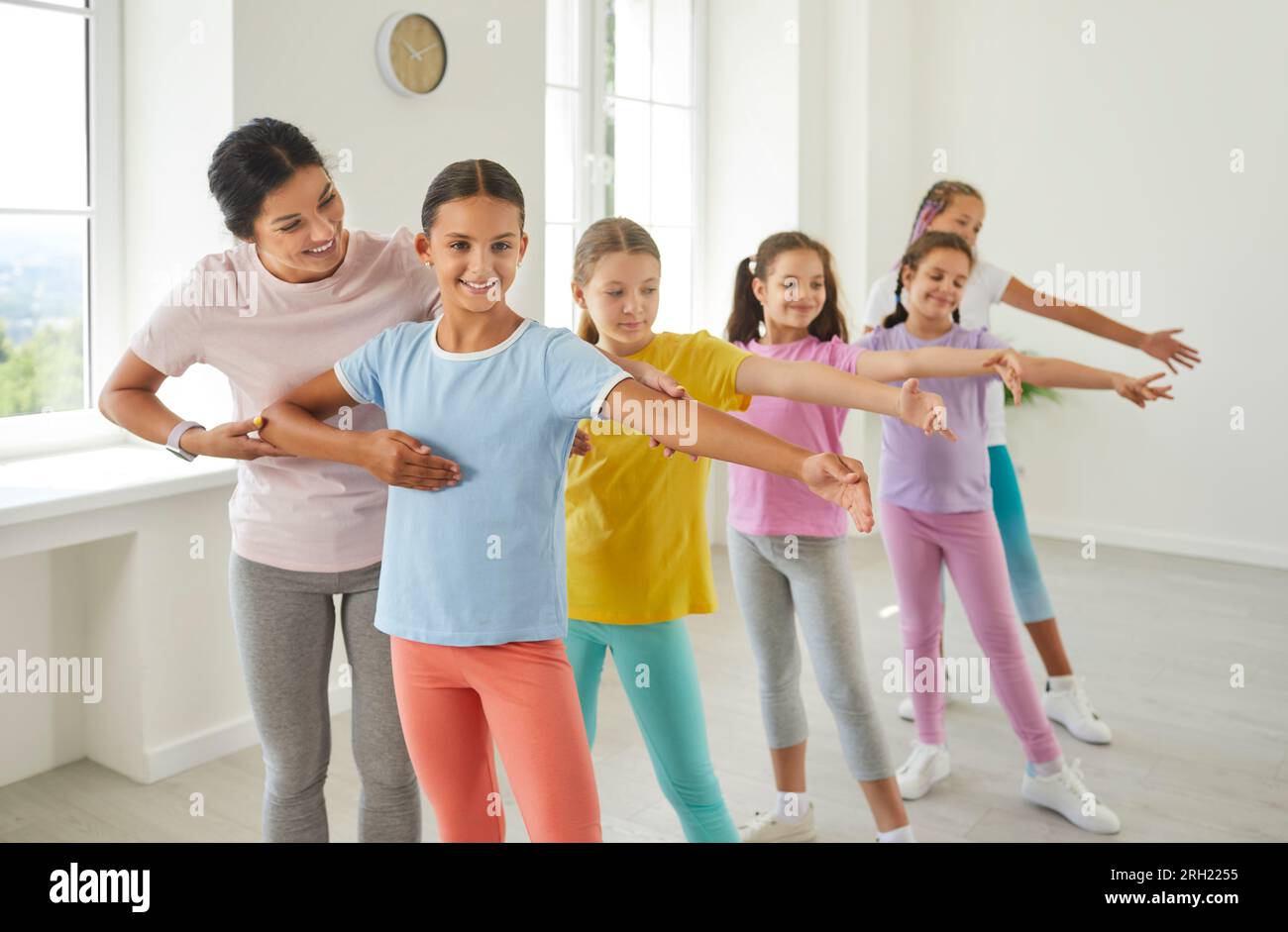 Female choreographer helping her students girls in doing a dance ...
