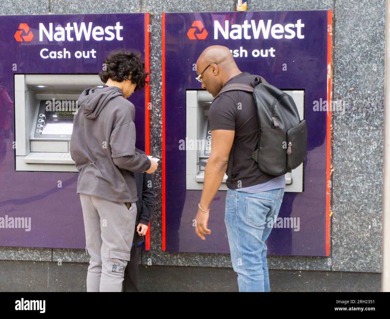 Two men using a cash dispenser at NatWest branch in Hammersmith, London, UK Stock Photo - Alamy