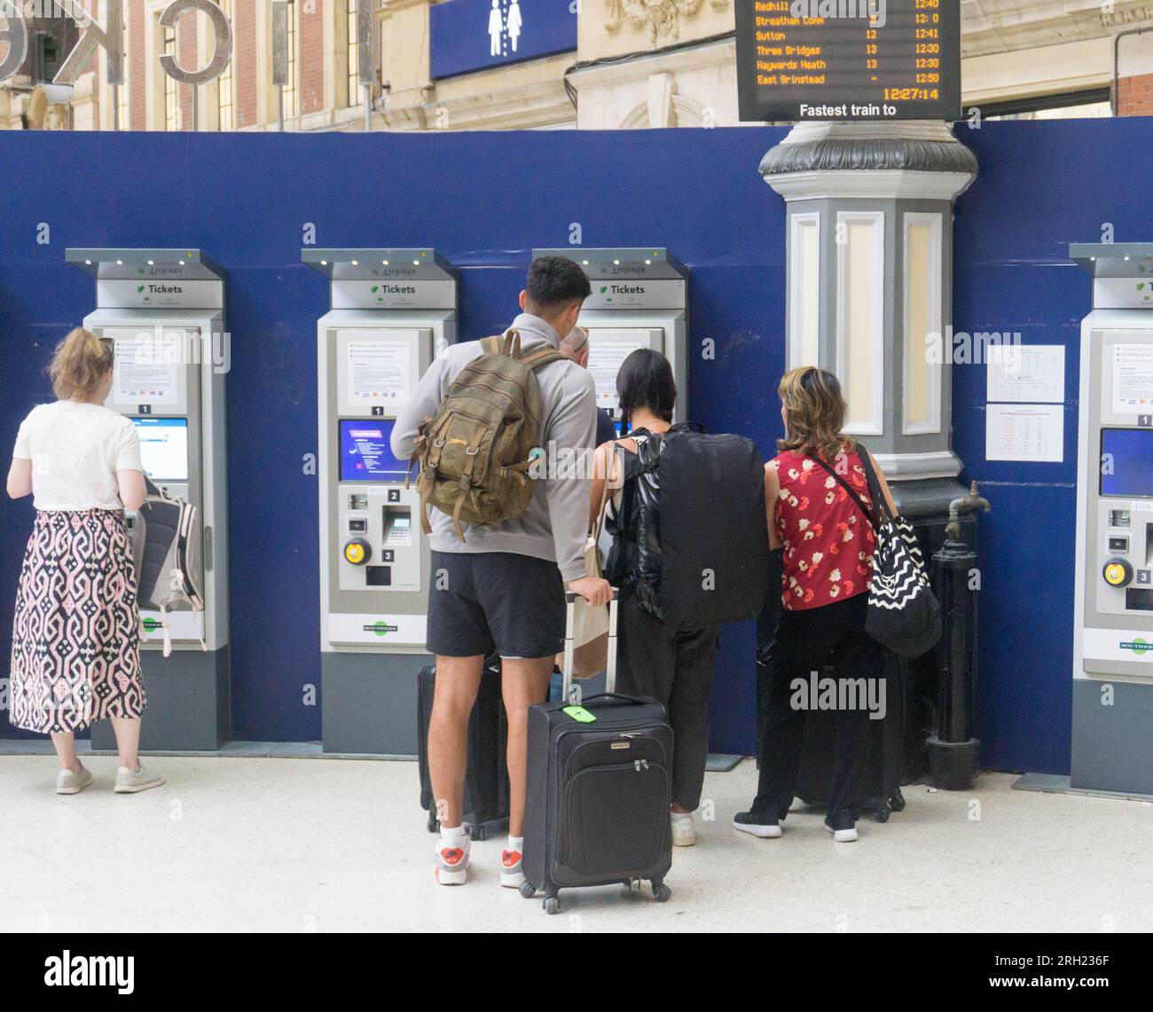 Travellers buy rail tickets at a vending machine at Victoria Station ...