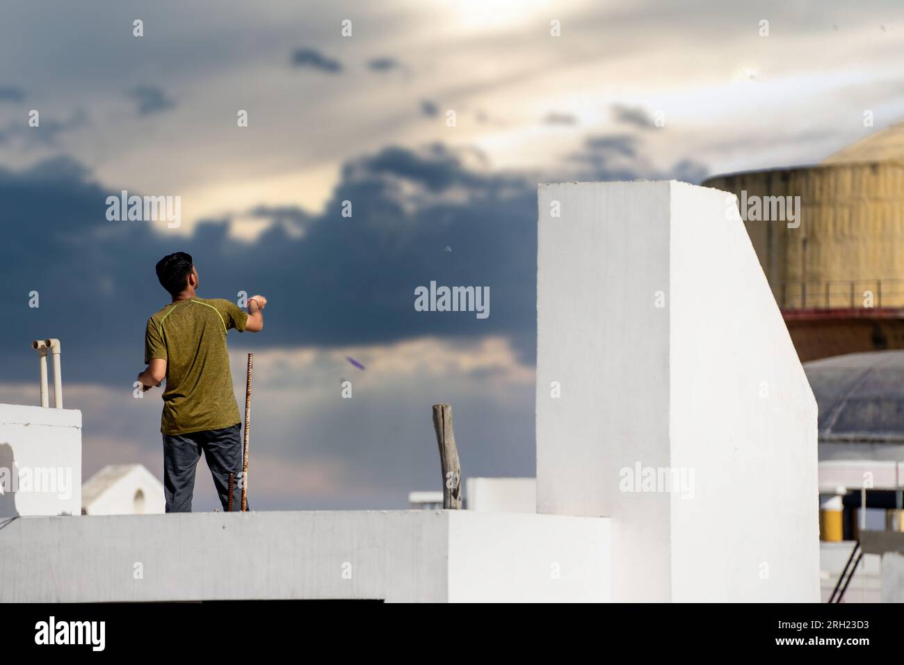 Slow motion shot of man on roof of white building flying kite with ...