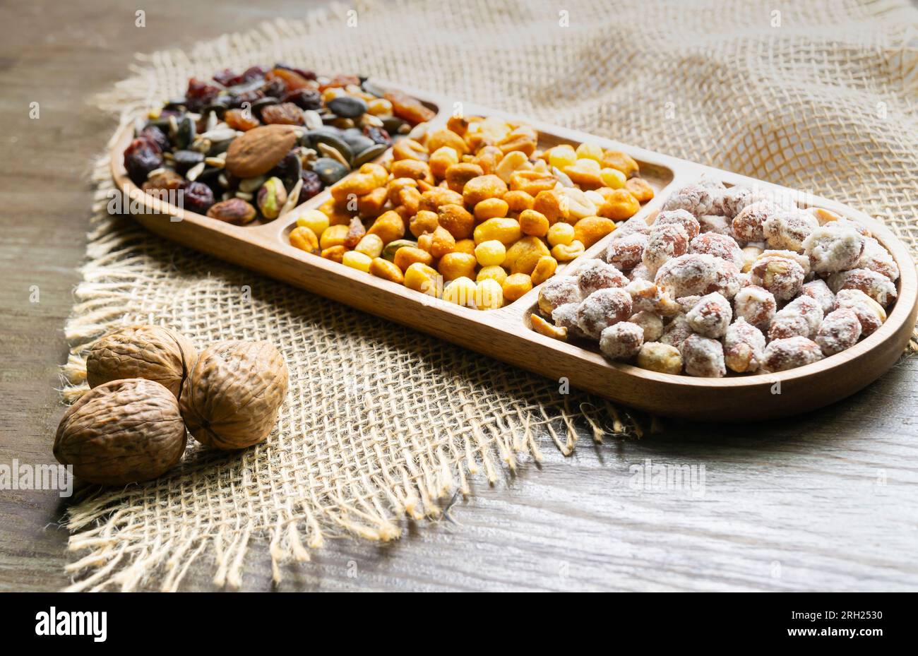 Dried fruits and seeds on a bamboo tray and walnuts. Horizontal shot ...