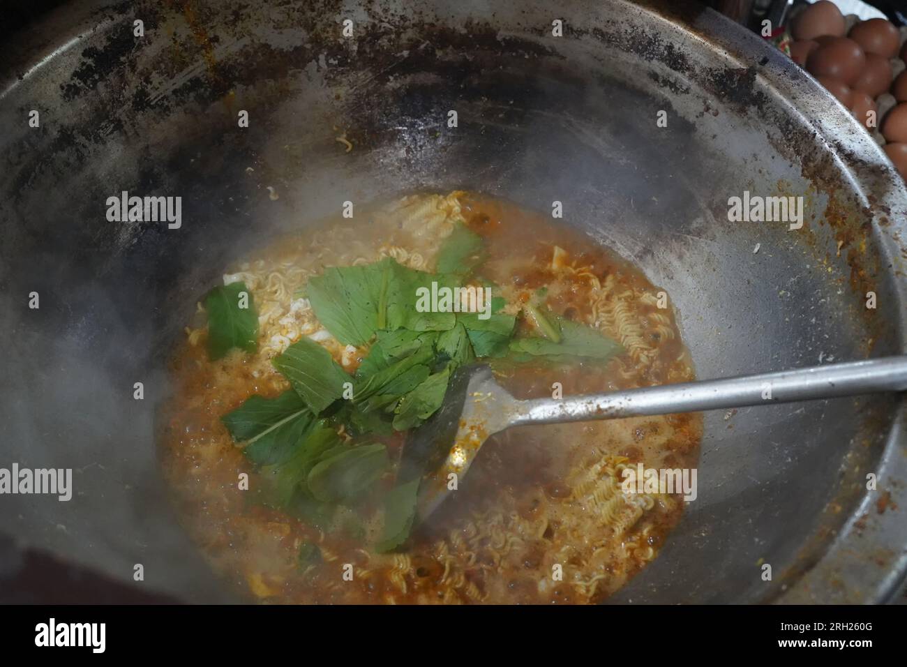 Prepare Indonesian instant noodles in a large frying pan with eggs in ...