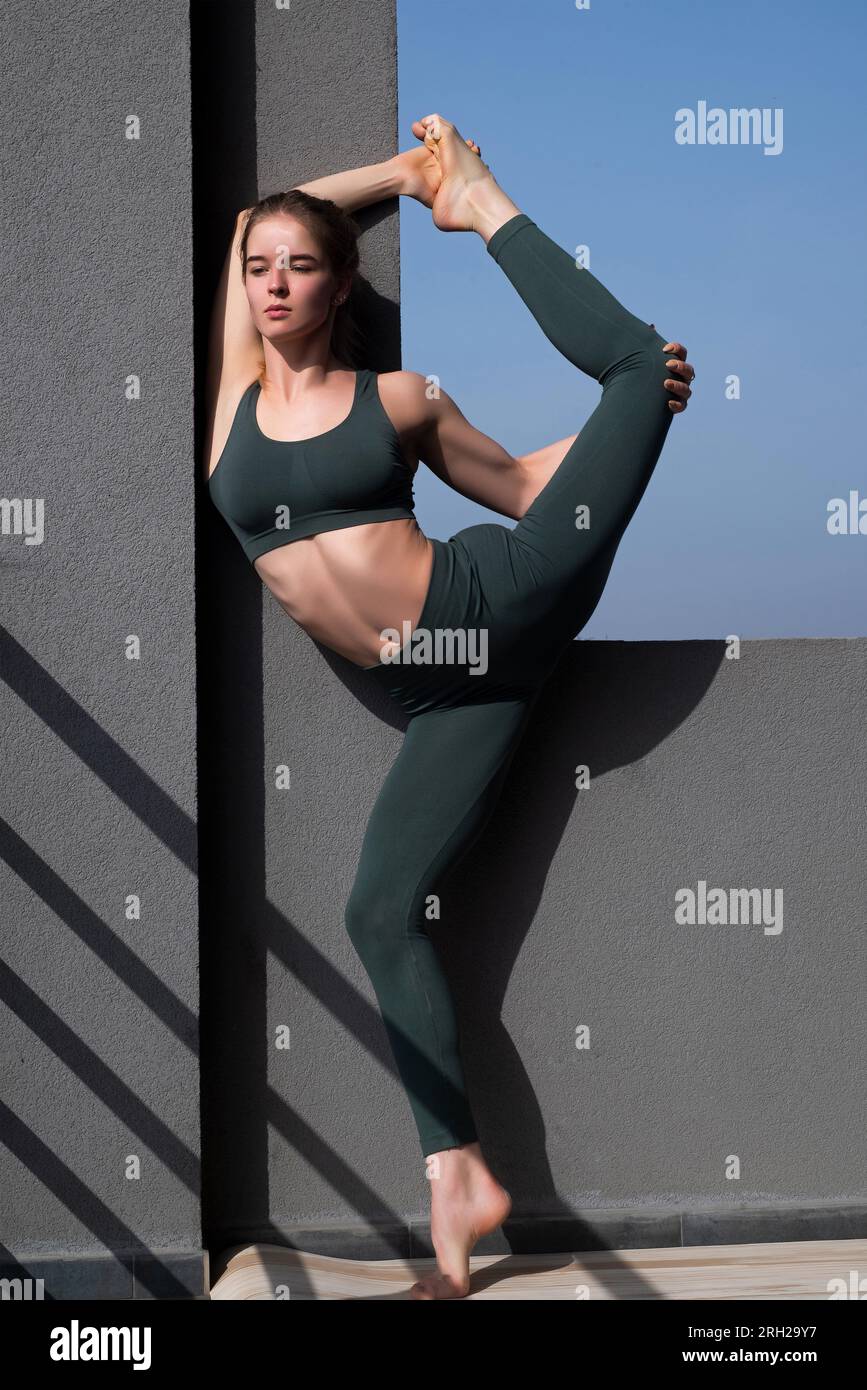 Young female woman workout, fitness training at the park. Girl stretching fit body. Leg-split ...