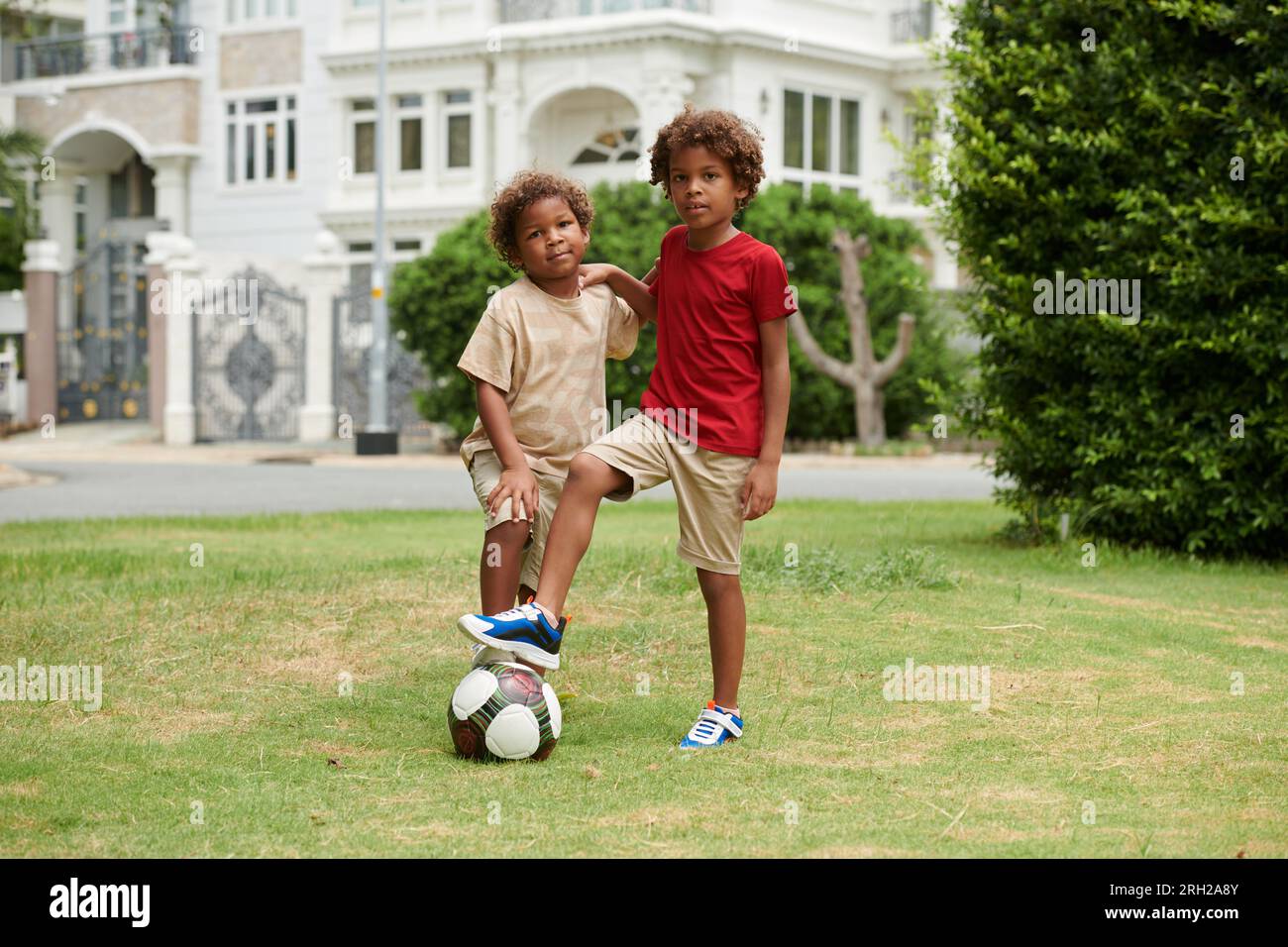 Joyful siblings playing game of soccer in backyard Stock Photo - Alamy