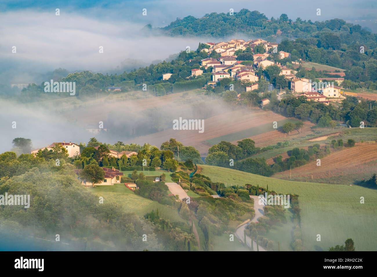 Rolling hills with small towns in the morning fog in Umbria, Italy ...