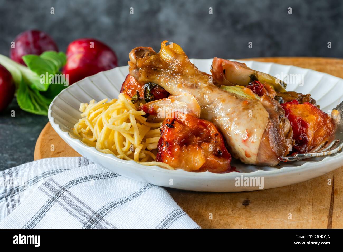 Chicken drumsticks with plums and pak choi Stock Photo - Alamy