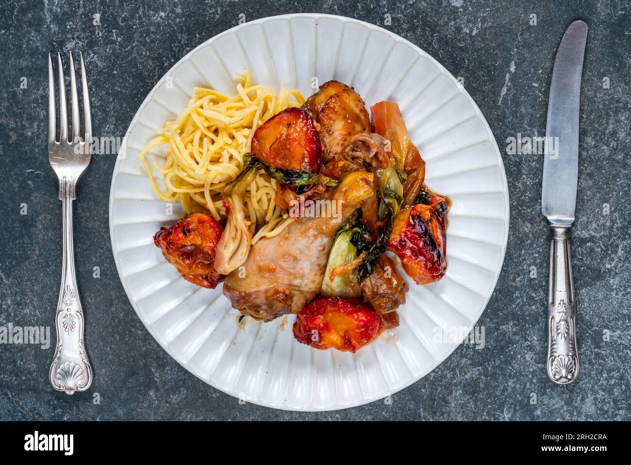 Chicken drumsticks with plums and pak choi Stock Photo - Alamy