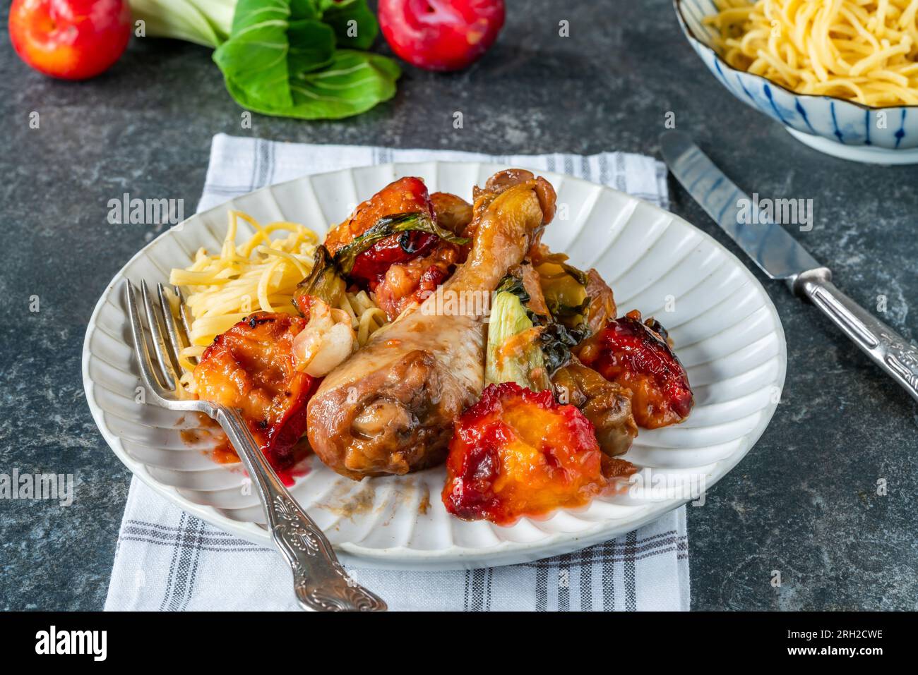 Chicken drumsticks with plums and pak choi Stock Photo - Alamy