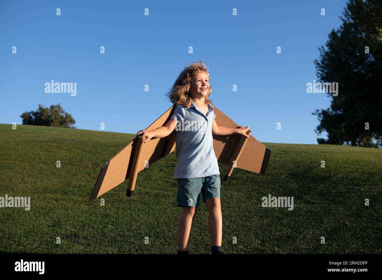 Child playing with toy plane wings in summer park. Innovation ...