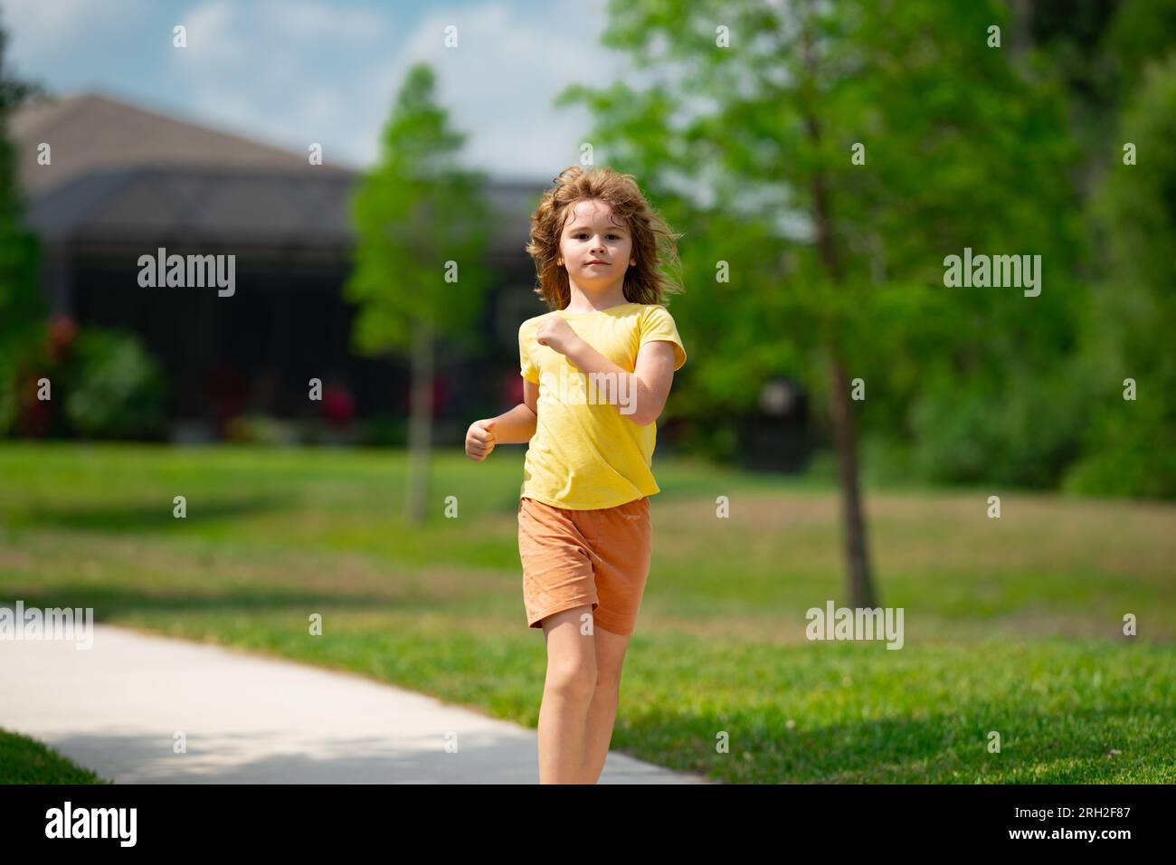 Cute kid boy running across american neighborhood street. Summer ...