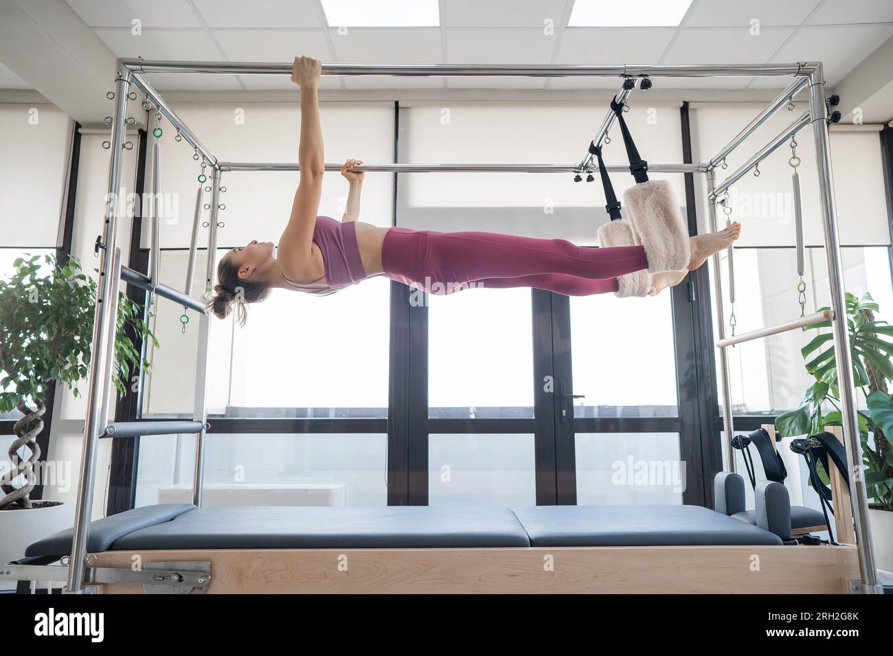 A caucasian woman is engaged in Pilates on a reformer simulator ...
