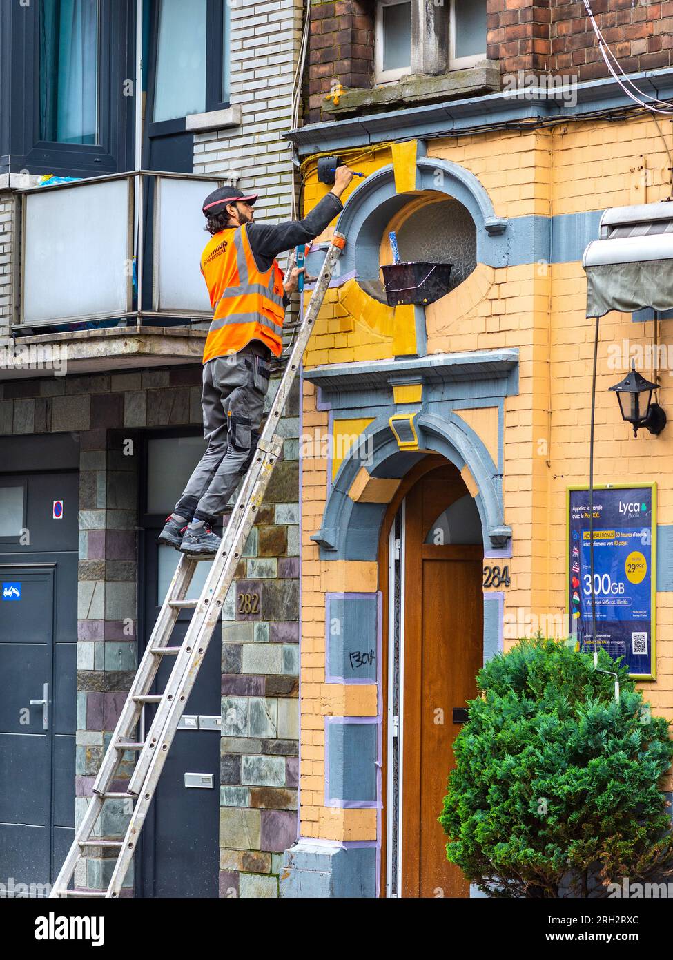 Man on ladder painting brickwork of house - Brussels, Belgium Stock ...