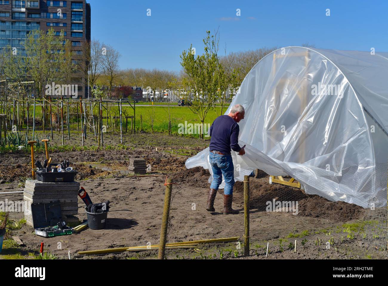A man is building a greenhouse made of agricultural plastic, stretched ...