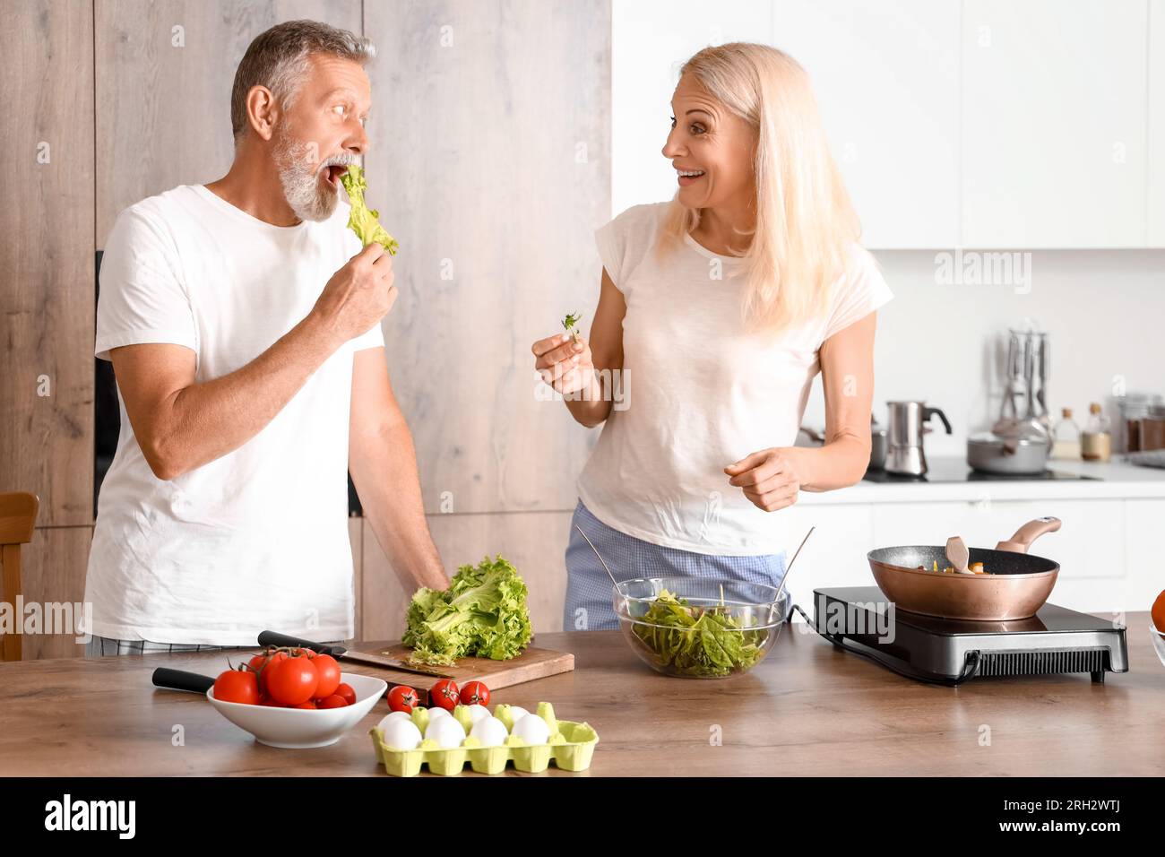 Mature couple eating vegetables in kitchen Stock Photo - Alamy