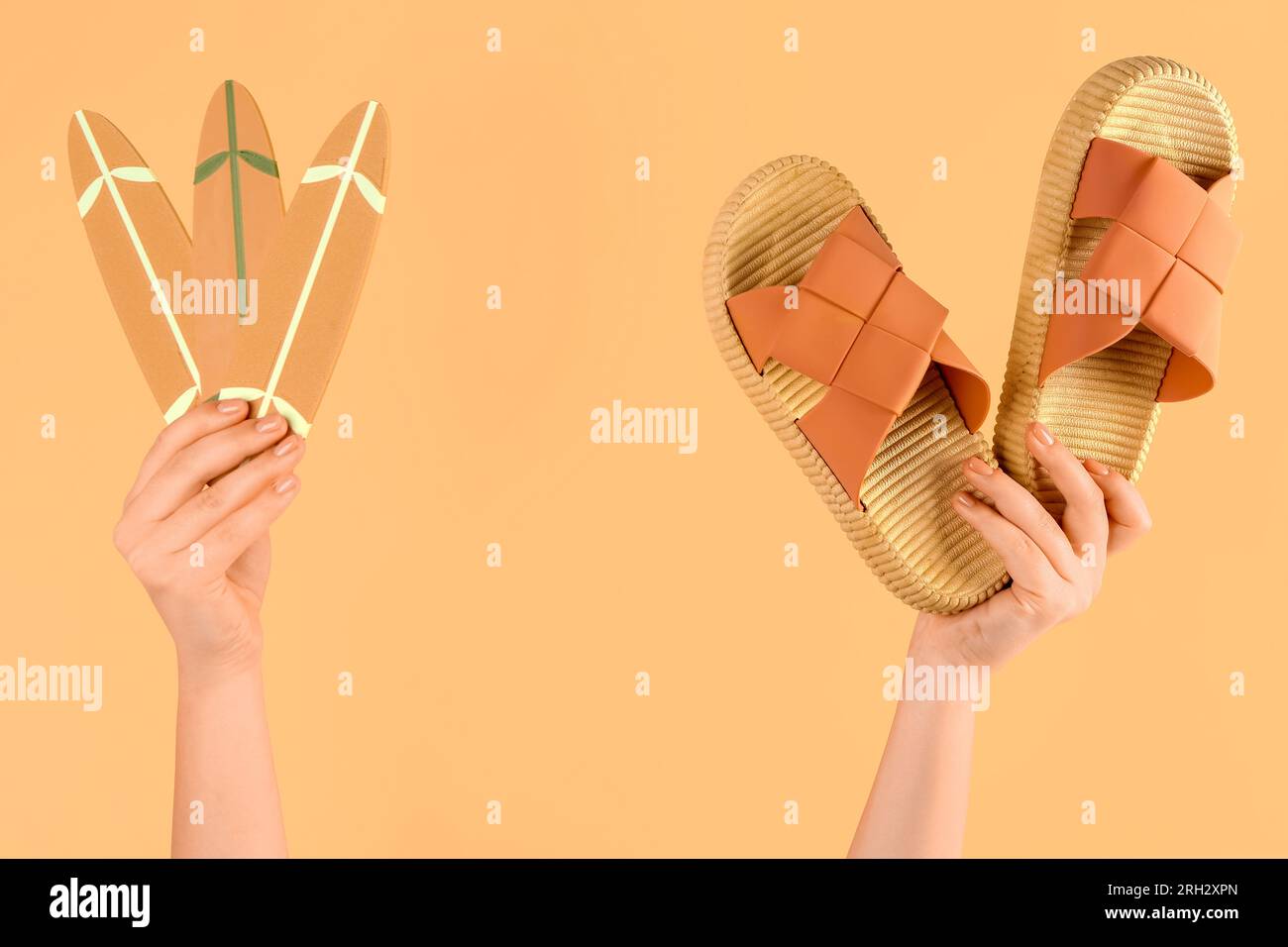Female hands with mini surfboards and flip flops on orange background ...