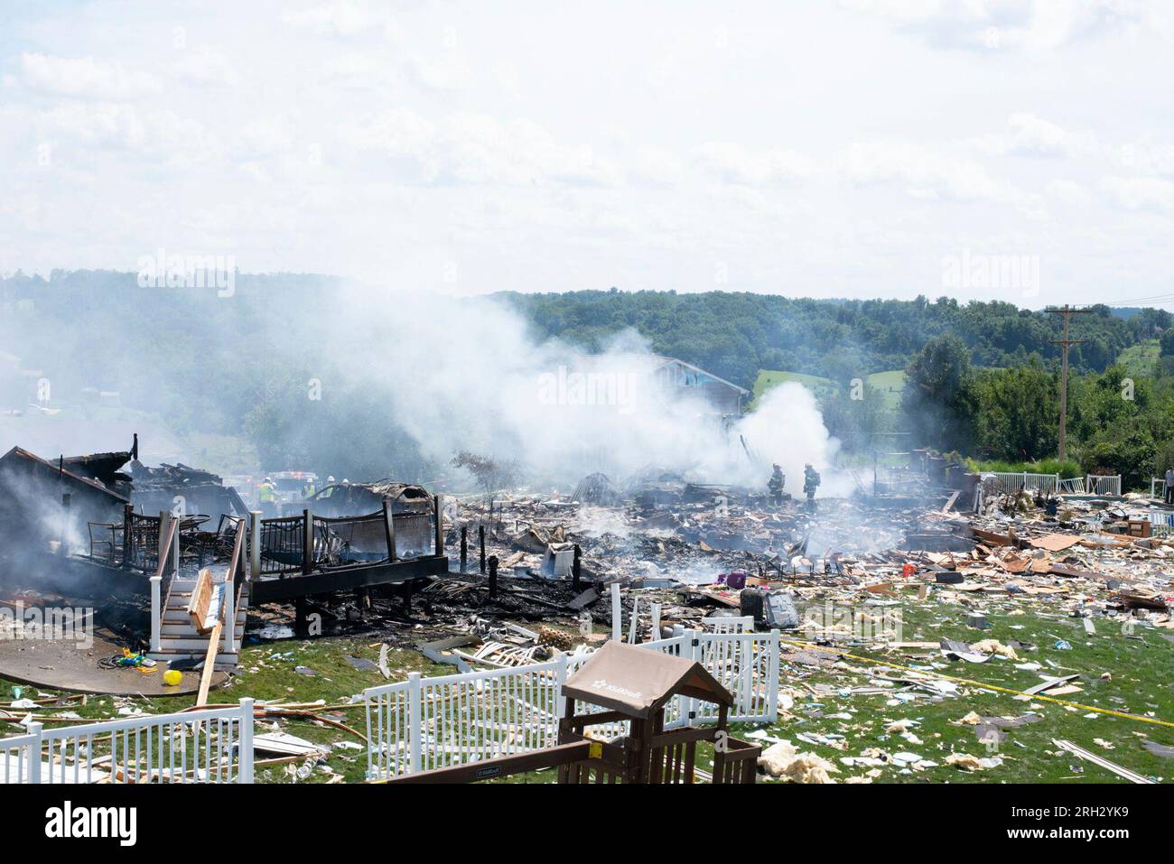 Two firefighters stand on the debris around the smoldering wreckage of ...
