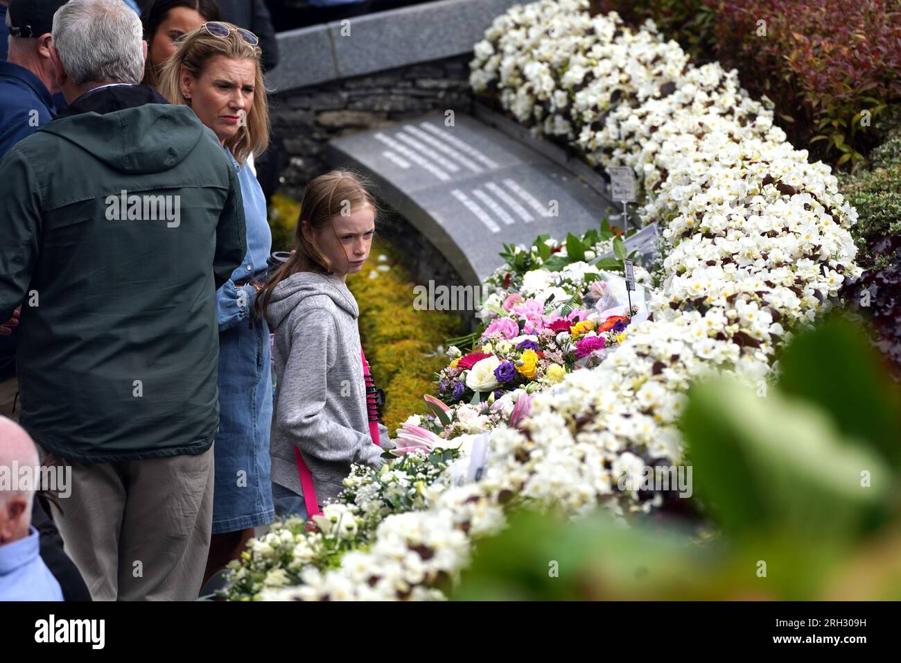 People gather at the monument following a service to mark the 25th ...