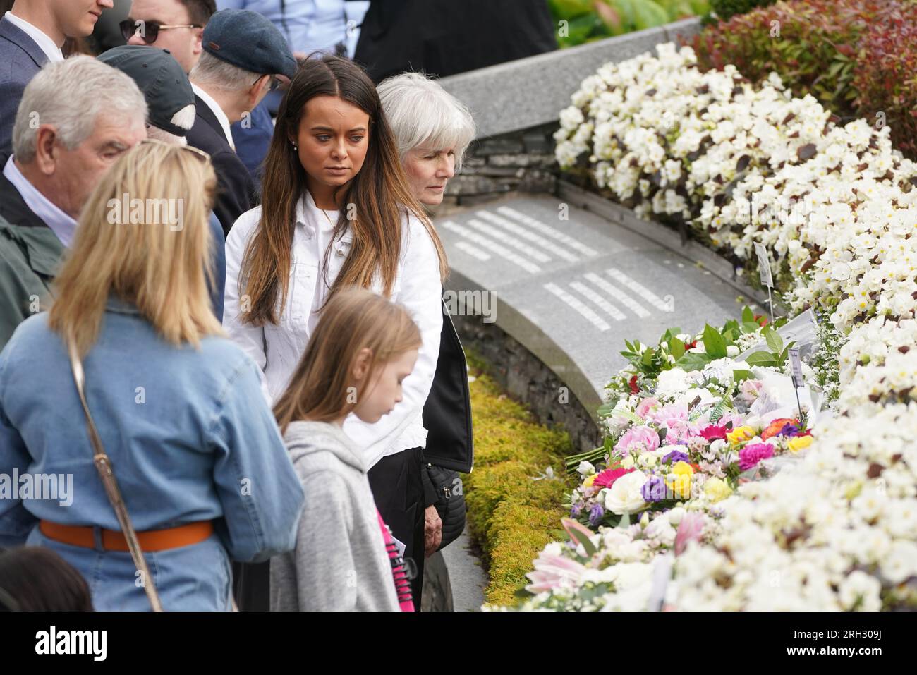 People gather at the monument following a service to mark the 25th ...