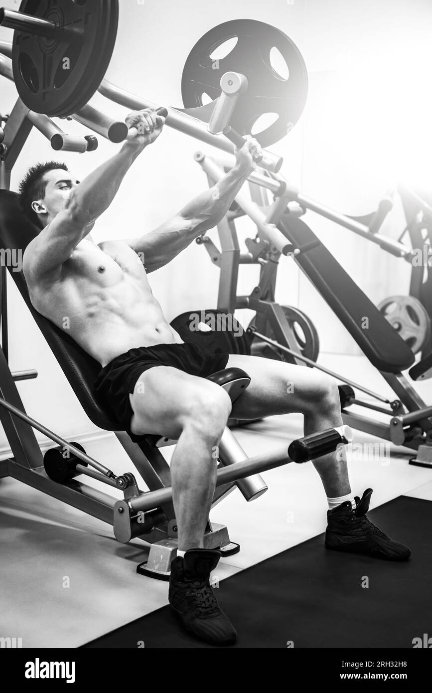 Strong muscular bodybuilder man doing the Machine Chest Press in a ...