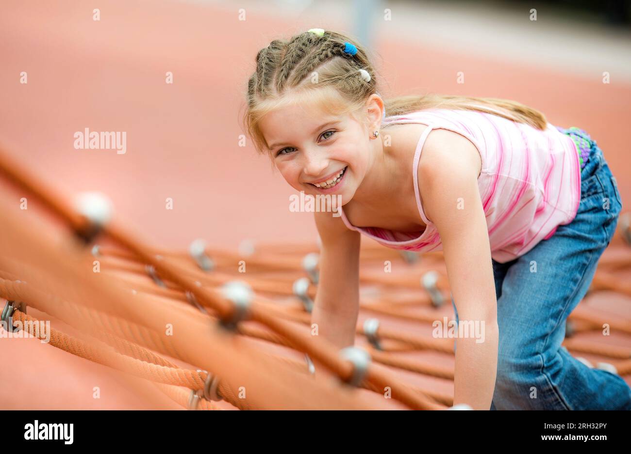 Happy beautiful smiling little girl playing at the playground and climb ...