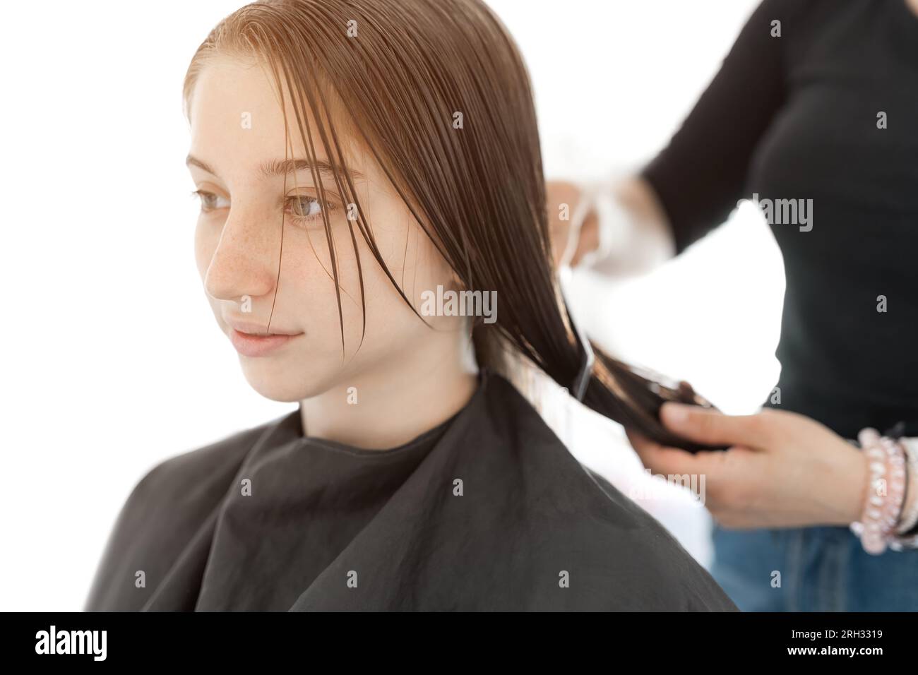 Hairdresser makes haircut for girl with scissor in room with daylight ...