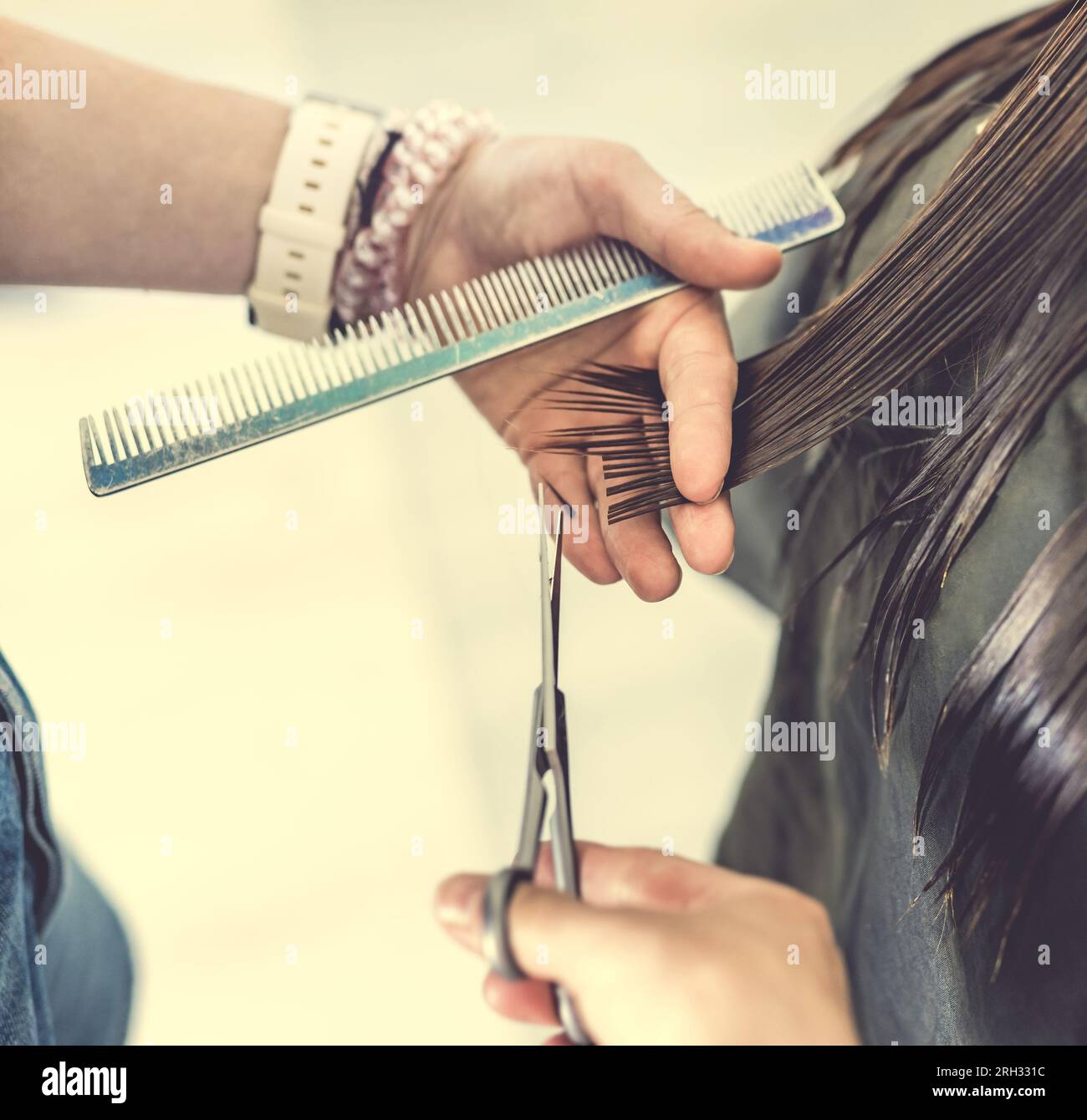 Hairdresser hands with scissors make hair cut in salon. Girl child ...