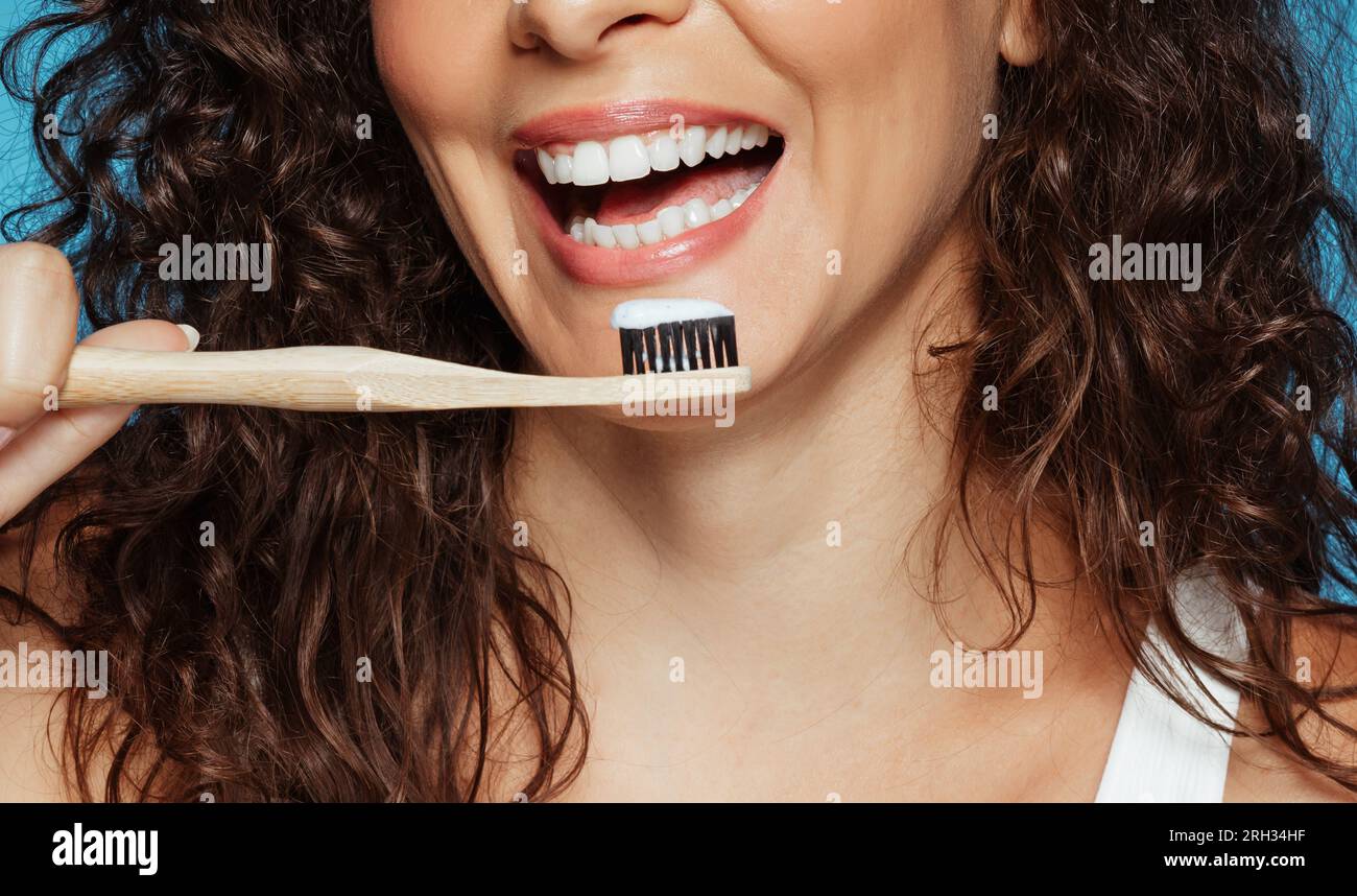 Laughing young european curly woman brushing teeth with toothpaste and ...