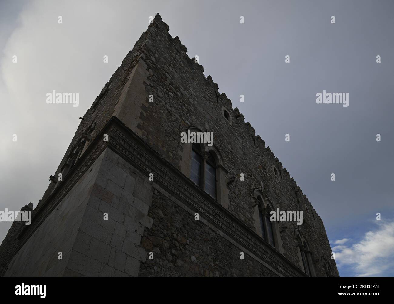 Medieval stone wall with Gothic style ogival windows and ancient Roman ...