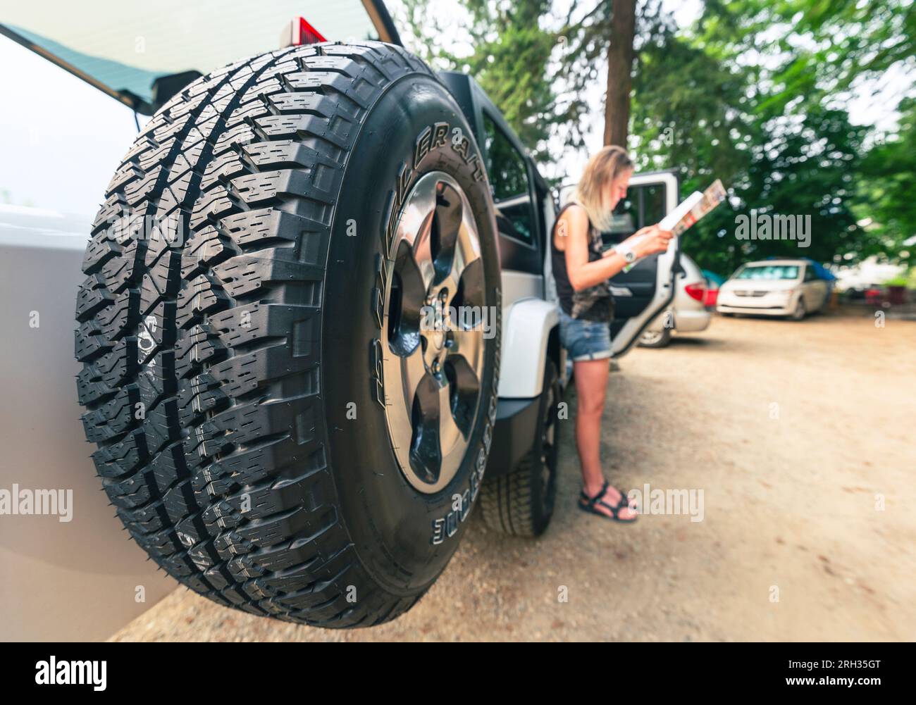 A woman studies a map by her car near the spare tyre on the back in ...