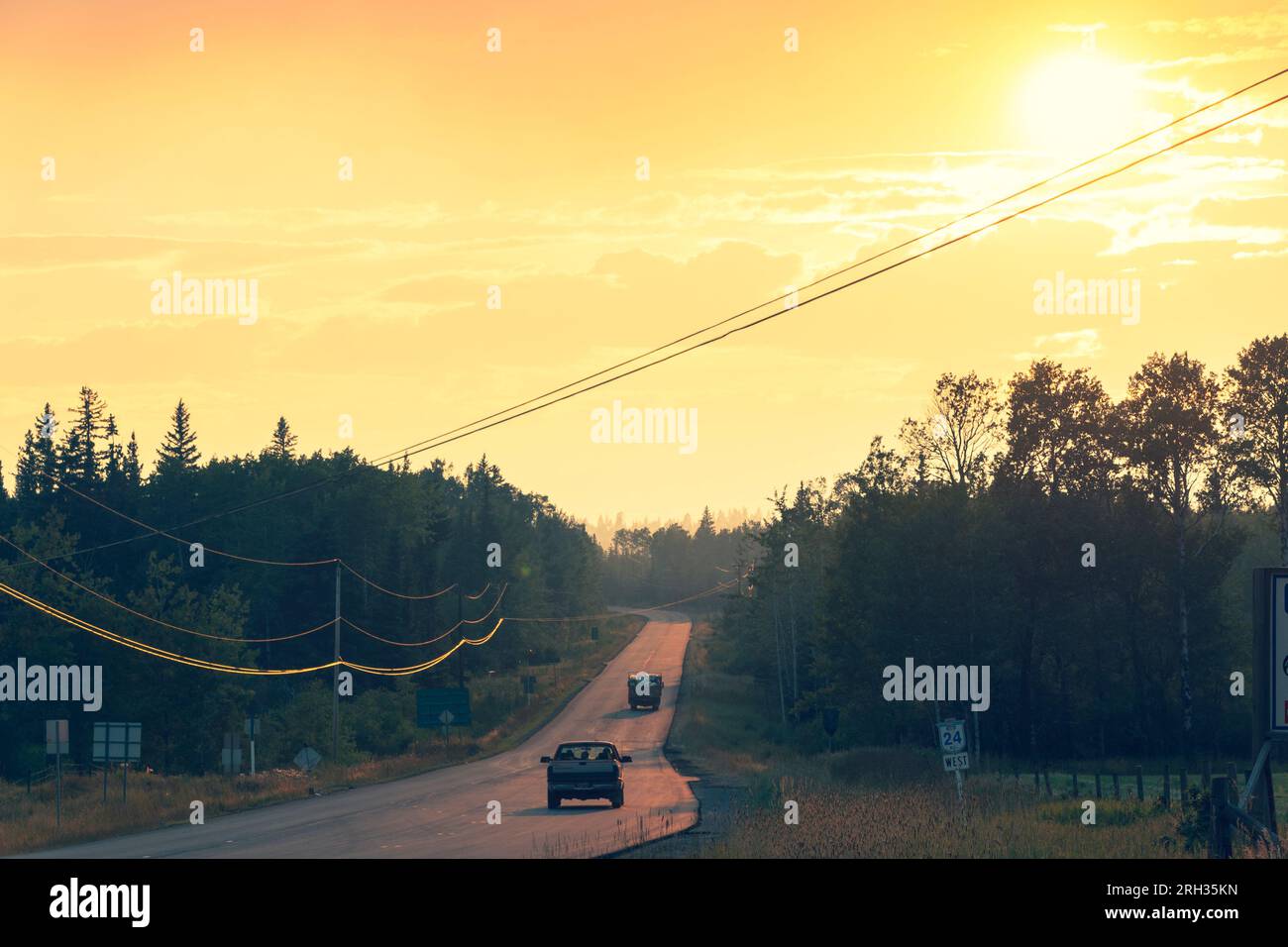 Cars travel along a Canadian highway as the sun cast a yellow glow in ...