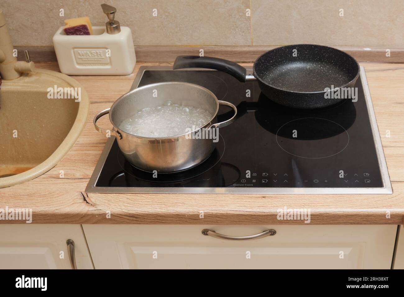 A pot of boiling water on a hot stove. Home beige kitchen with brown ...