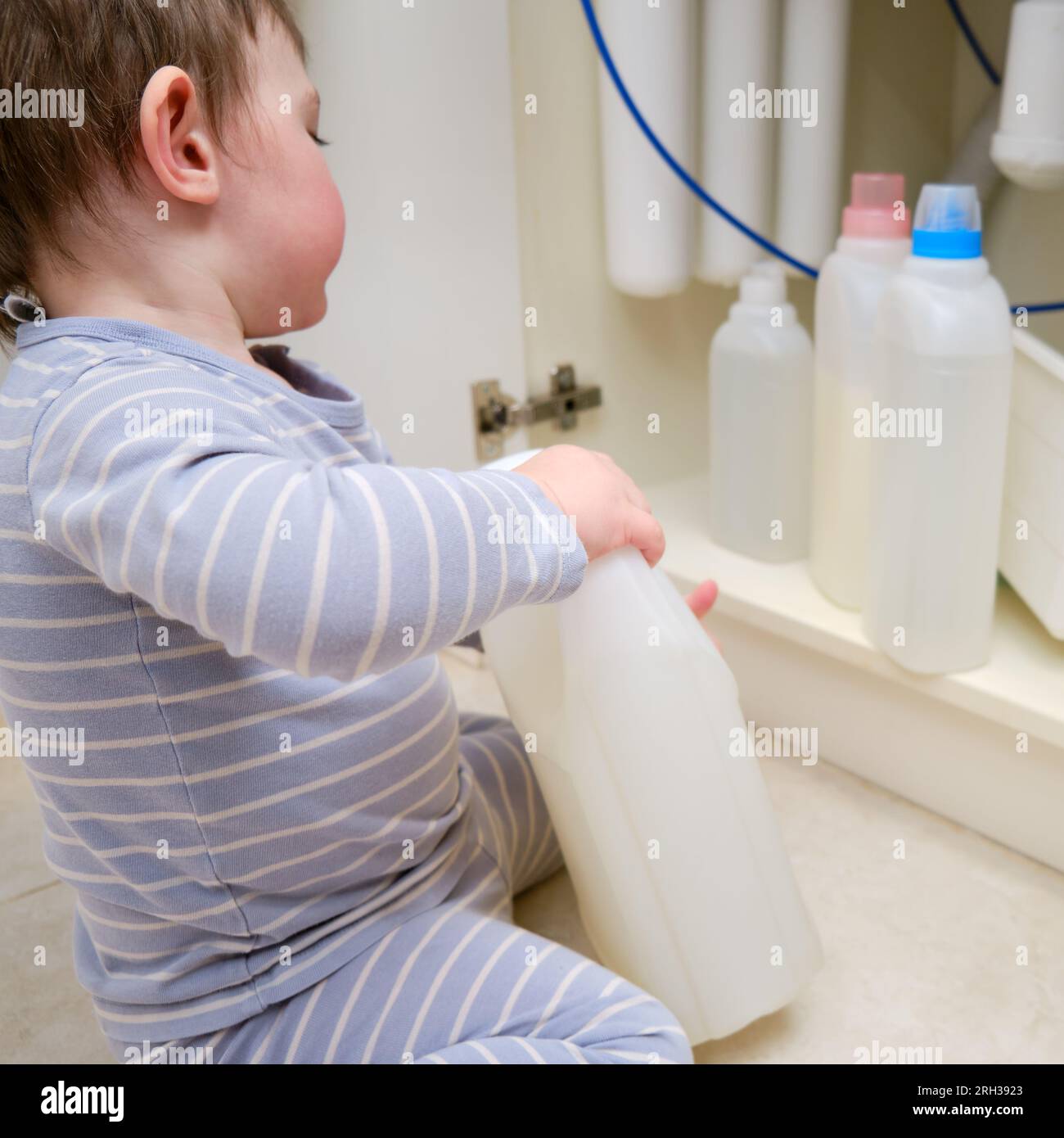 A child is playing with chemical cleaning products under the sink in ...