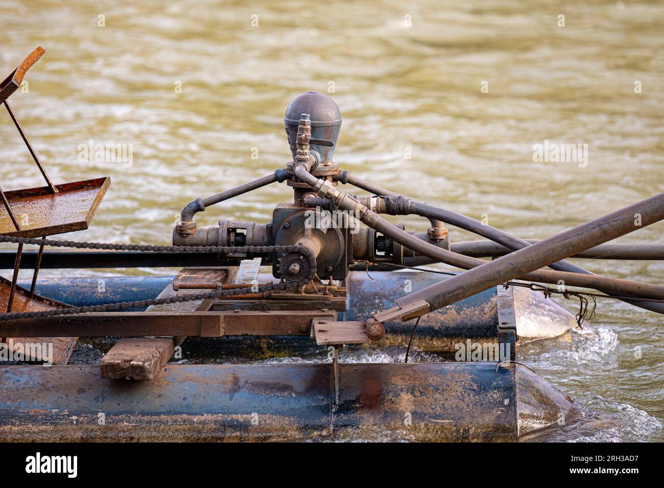closeup on water pumping system by water wheel and pump floating in a ...