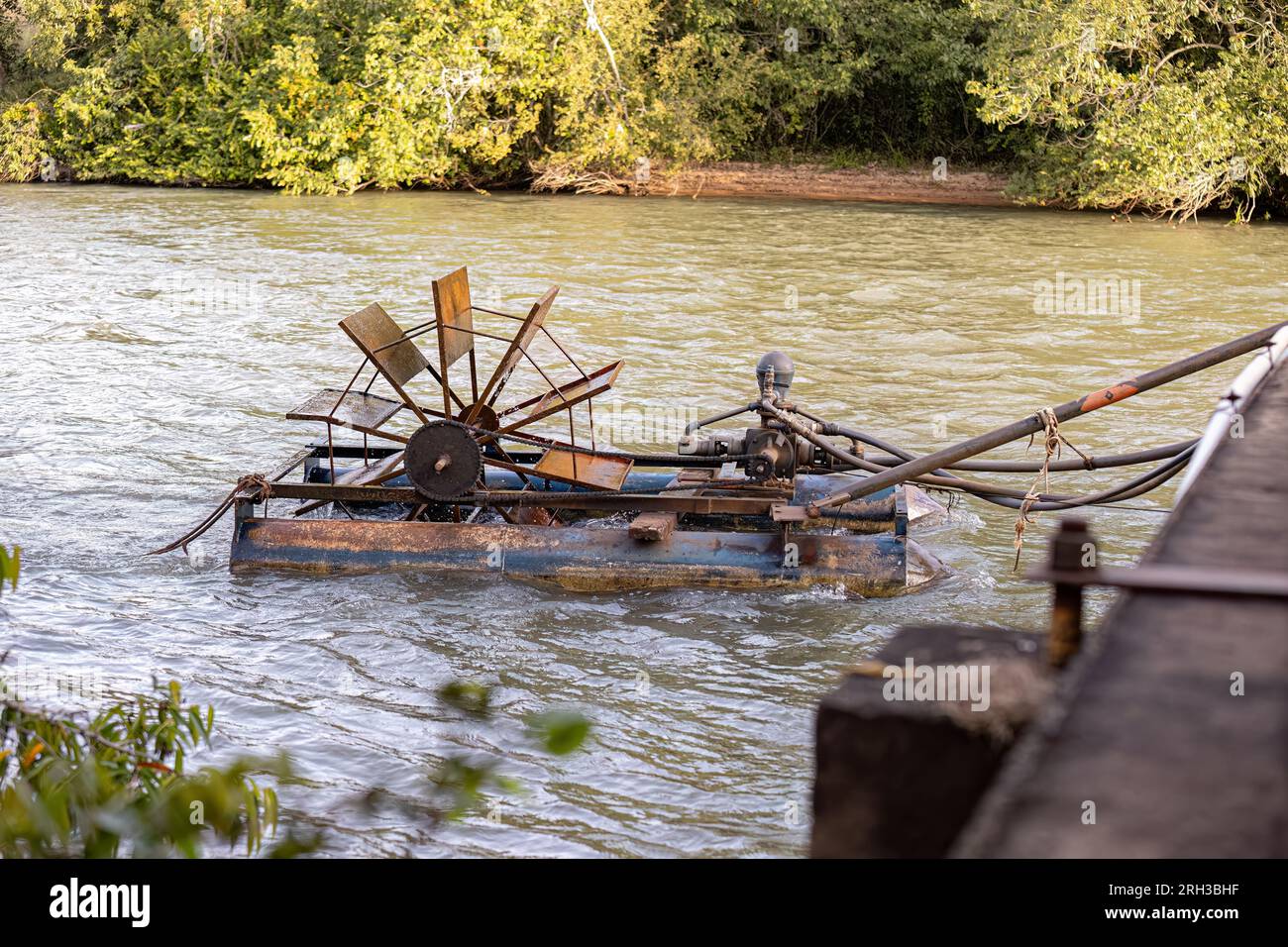 closeup on water pumping system by water wheel and pump floating in a ...