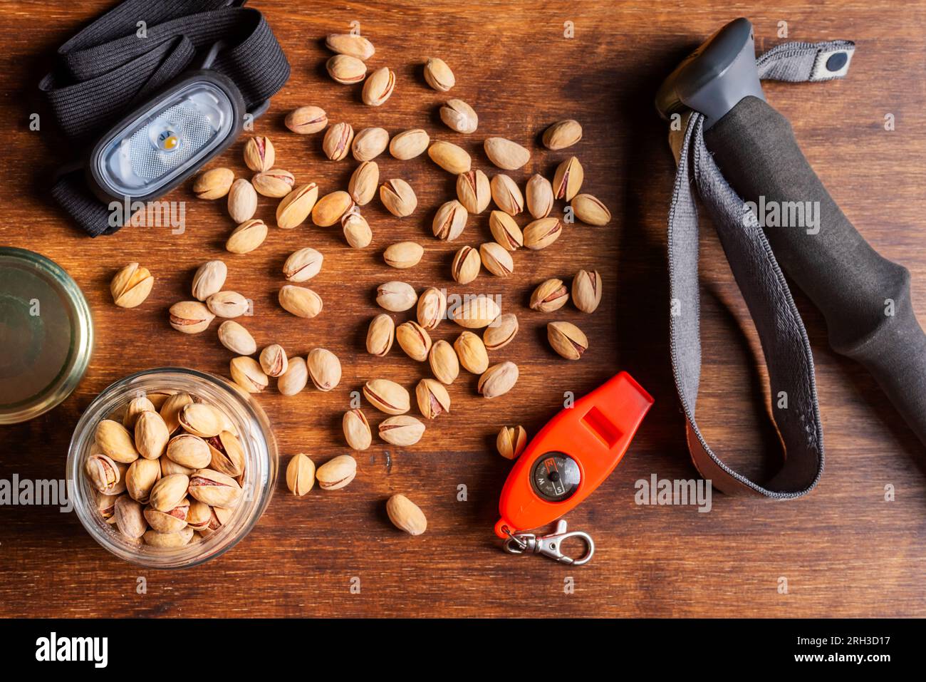 Pistachio nuts next to a full jar, a flashlight, a compass with a ...