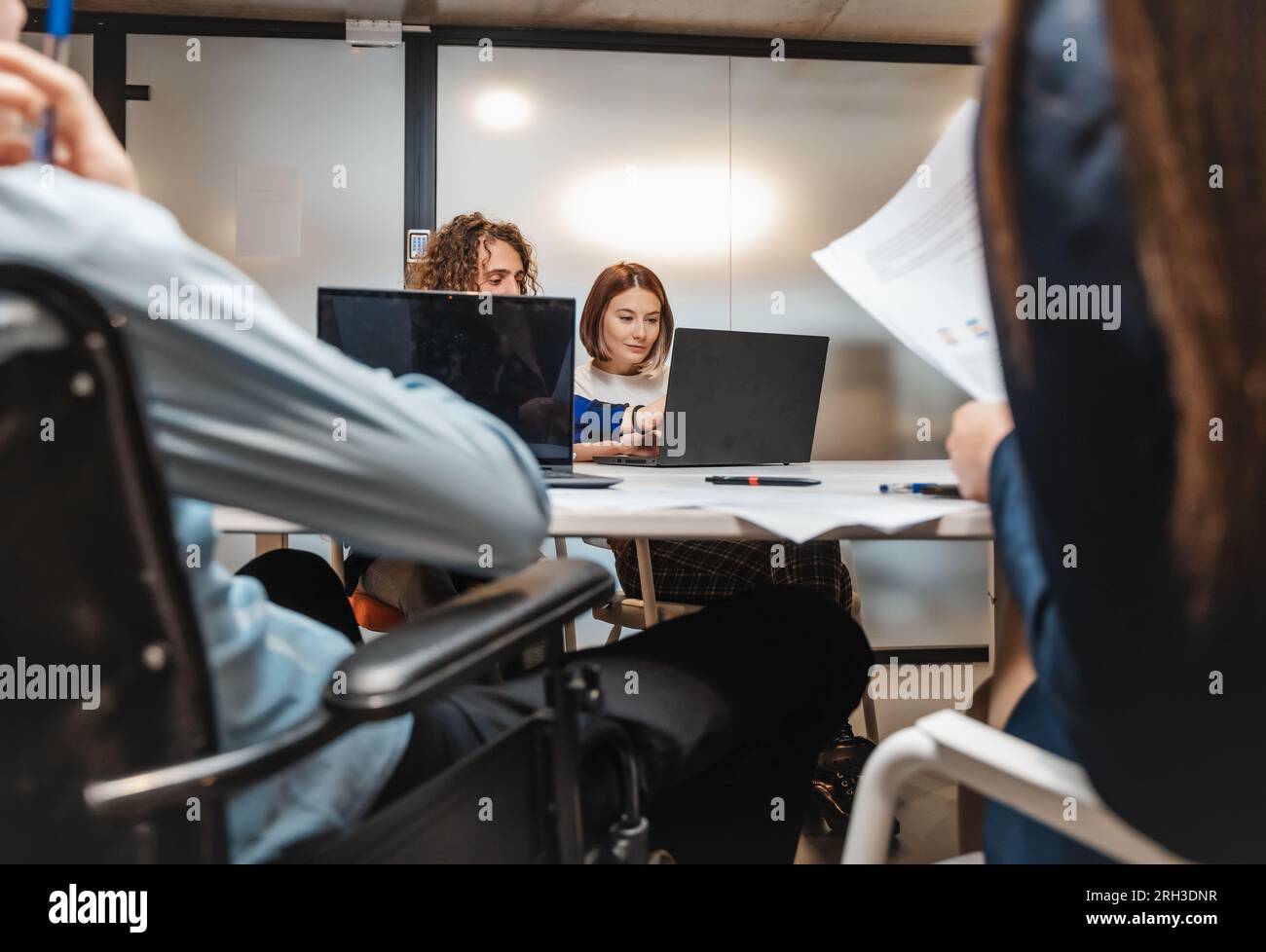 Group of business people working at the office. Experienced male programmer fixing his female ...