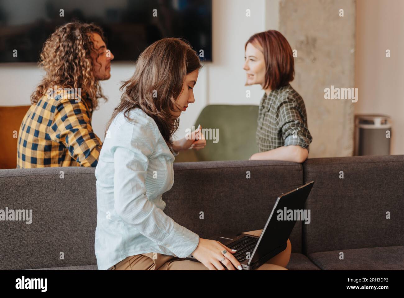 Beautiful female freelance woman working on lap top while her partners ...