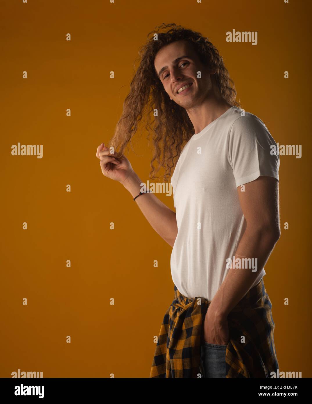 Strong smiley man posing in studio on orange background touching his ...