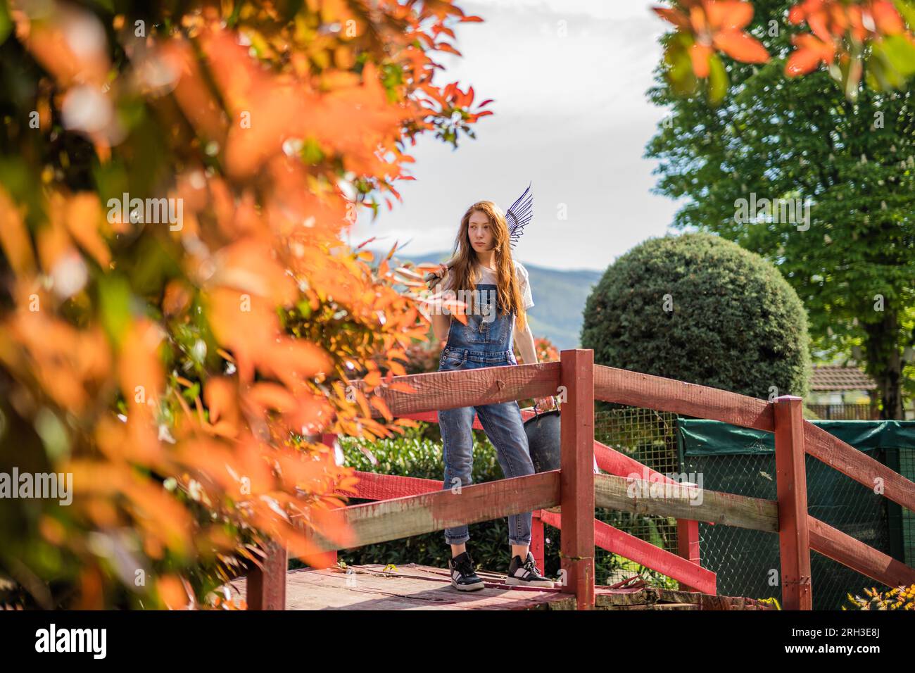 Stunning ginger gardener looking at something while standing on red ...