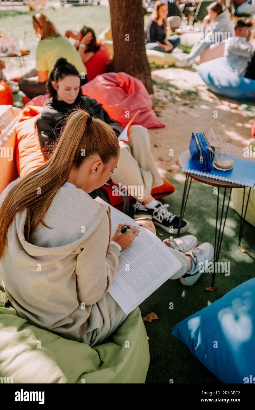 A blonde girl is underlining the most important part from the book ...